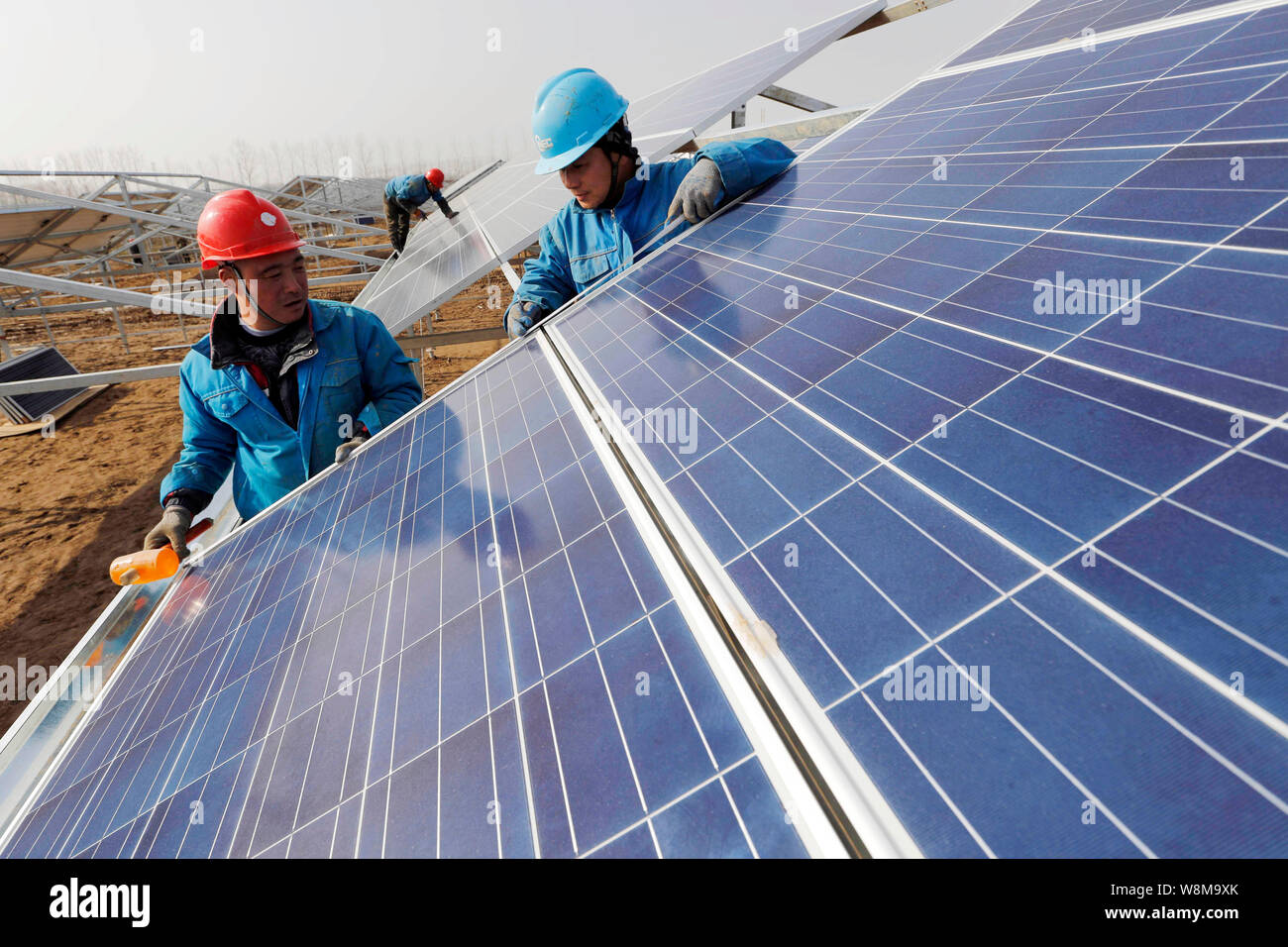 --FILE--Chinese workers install solar panels at a photovoltaic power ...