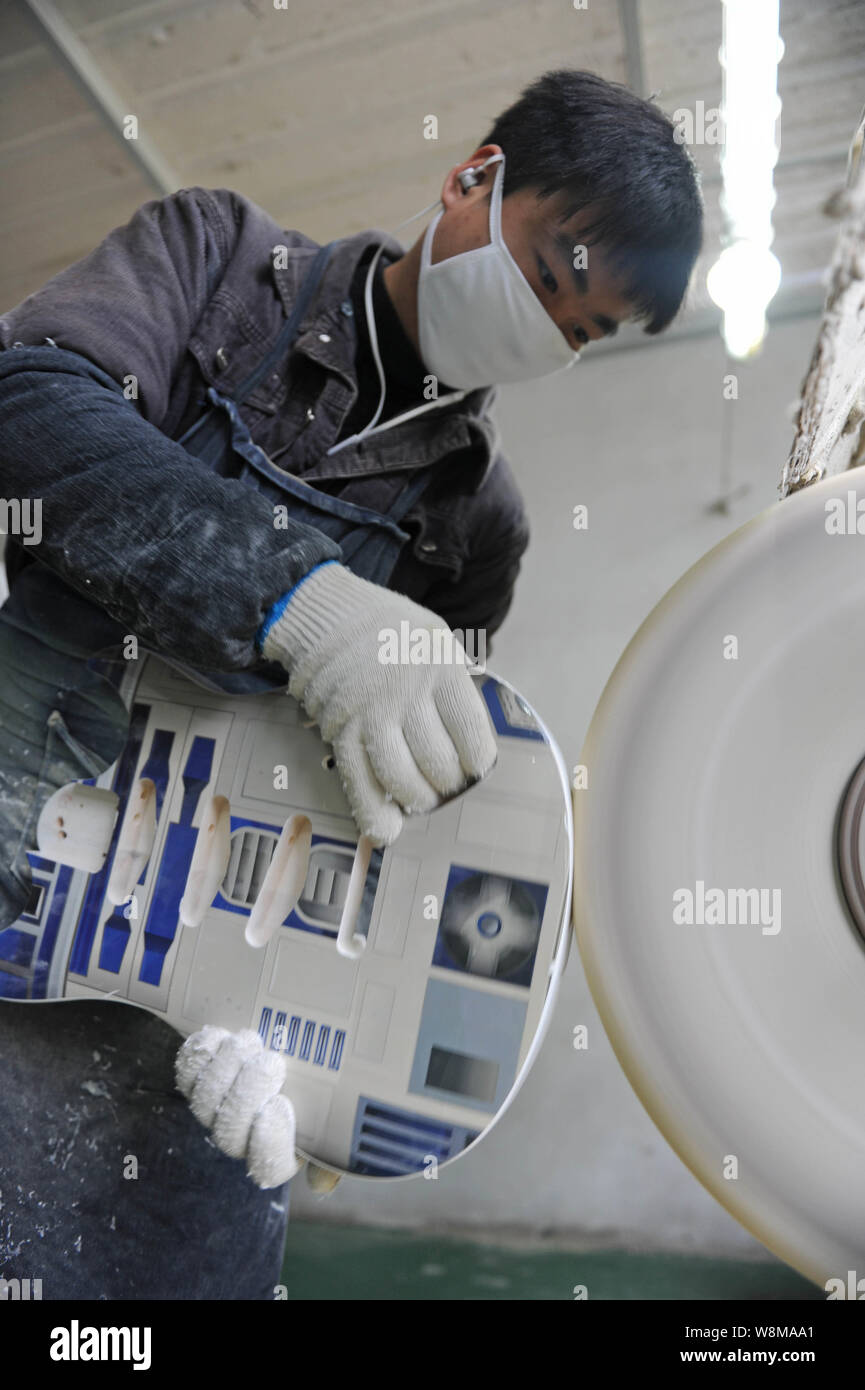 --FILE--A Chinese worker polishes an electric guitar at a musical ...