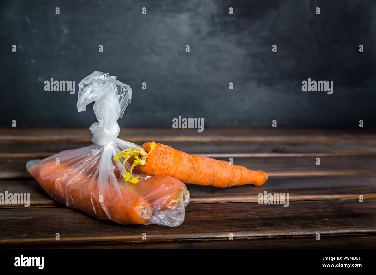 concept plasic free carrots in a plastic bag on a brown background with ...