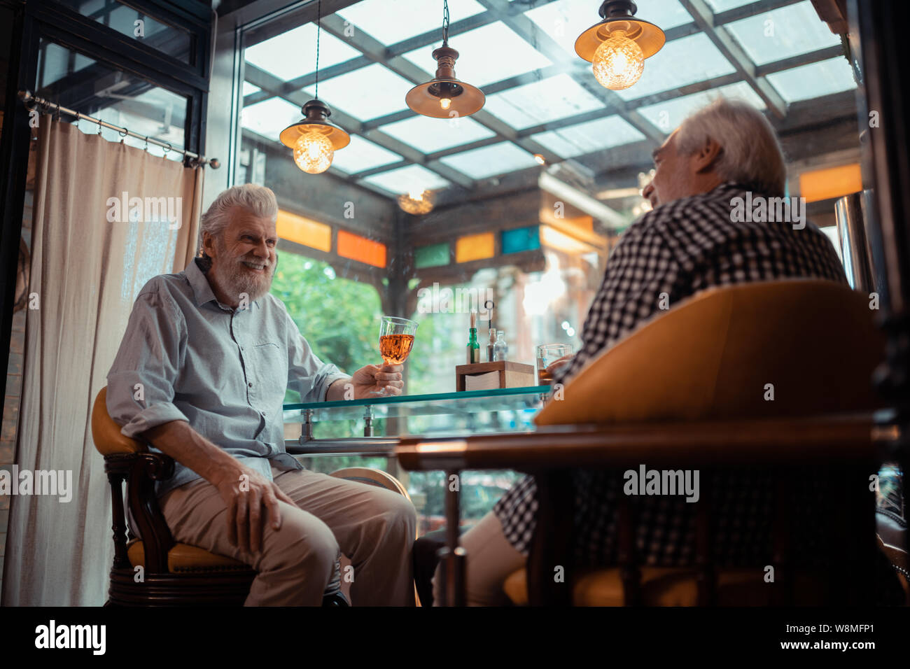 Man smiling while drinking alcohol with friend Stock Photo - Alamy