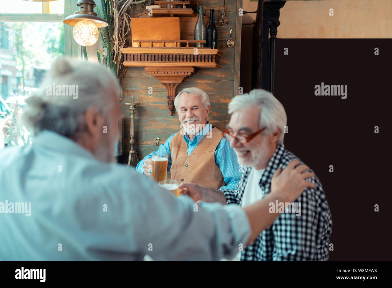 Pensioners laughing while drinking beer in pub Stock Photo - Alamy