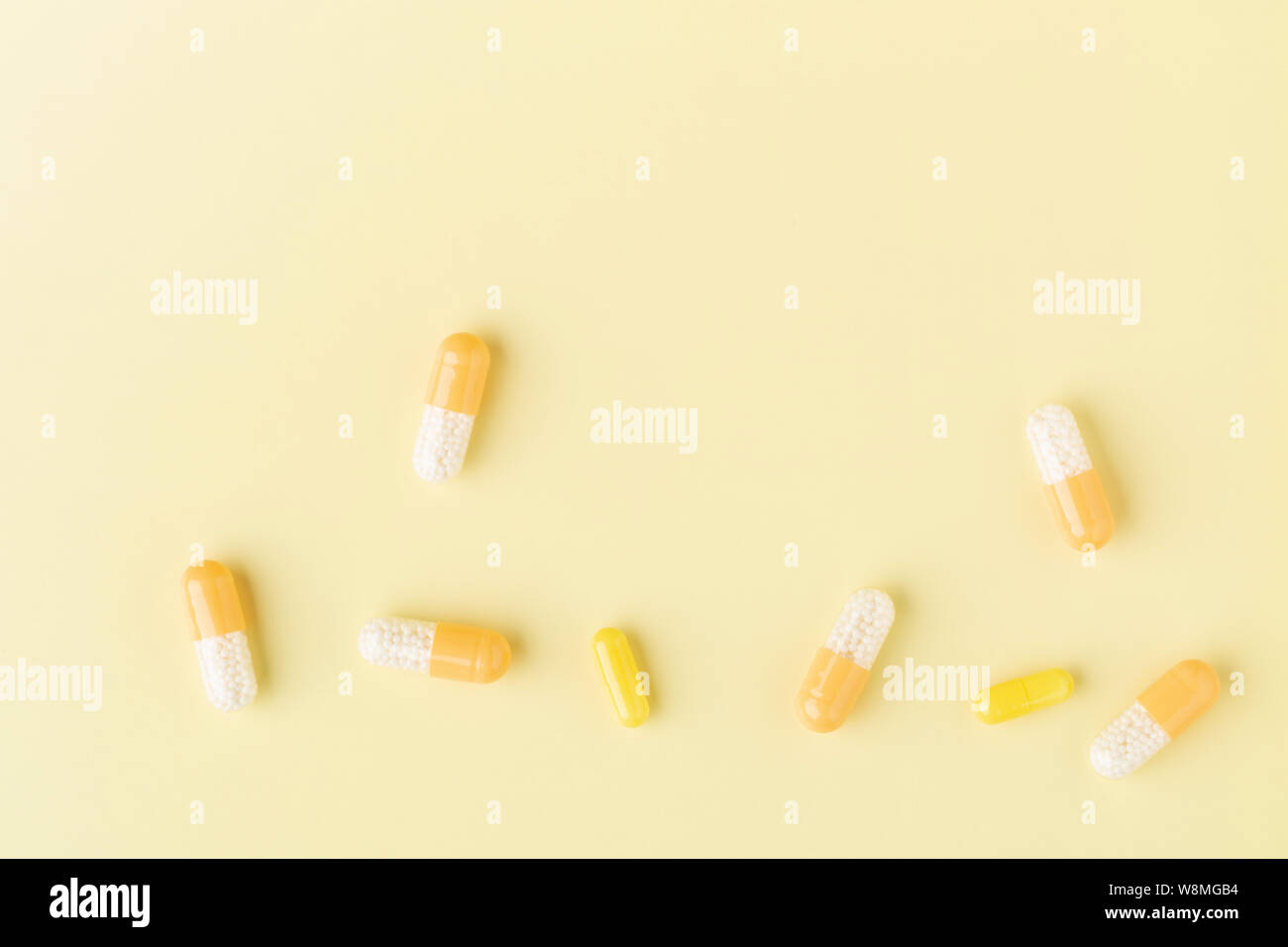 A few white-yellow drug capsules on the yellow background Stock Photo ...