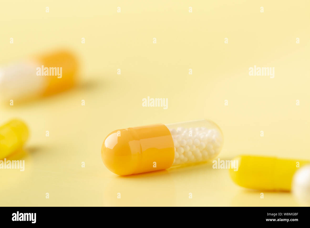 A few white-yellow drug capsules on the yellow background Stock Photo ...