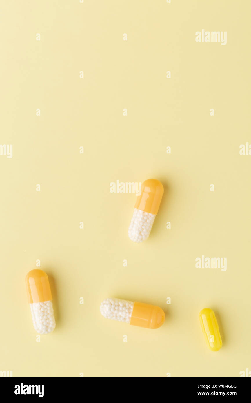 A few white-yellow drug capsules on the yellow background Stock Photo ...