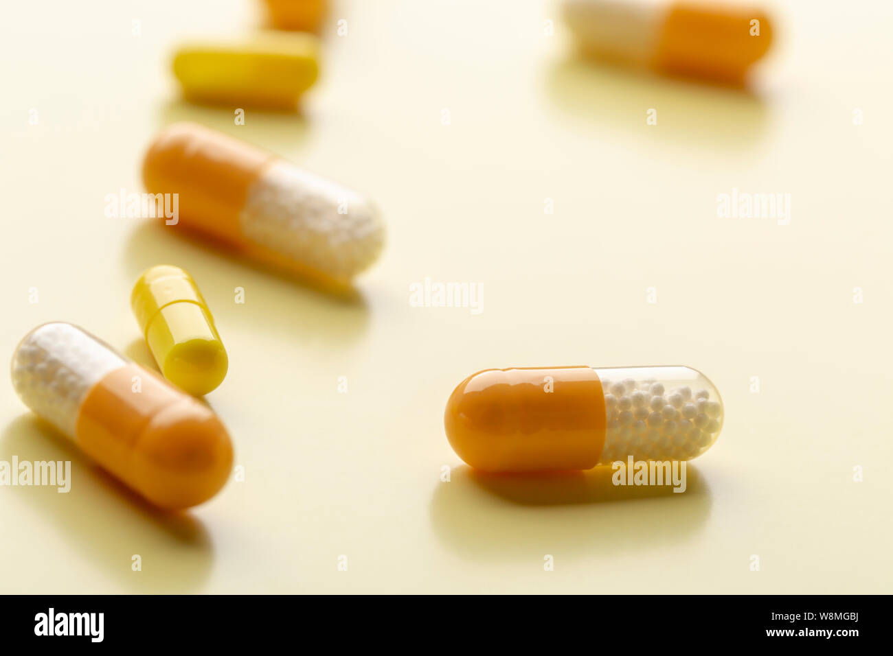 A few white-yellow drug capsules on the yellow background Stock Photo ...