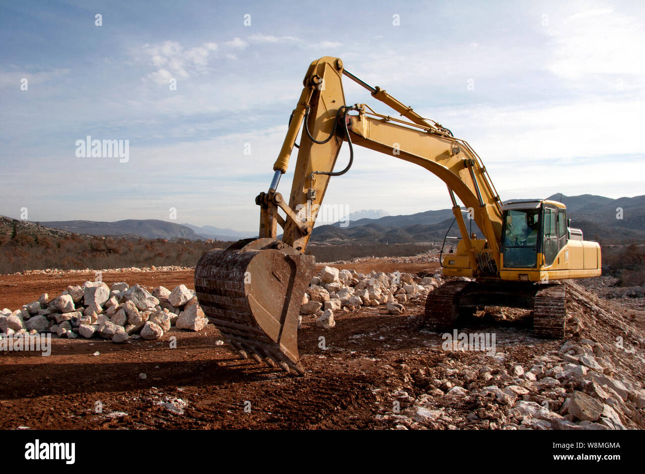 Yellow backhoe working on construction of road Stock Photo - Alamy
