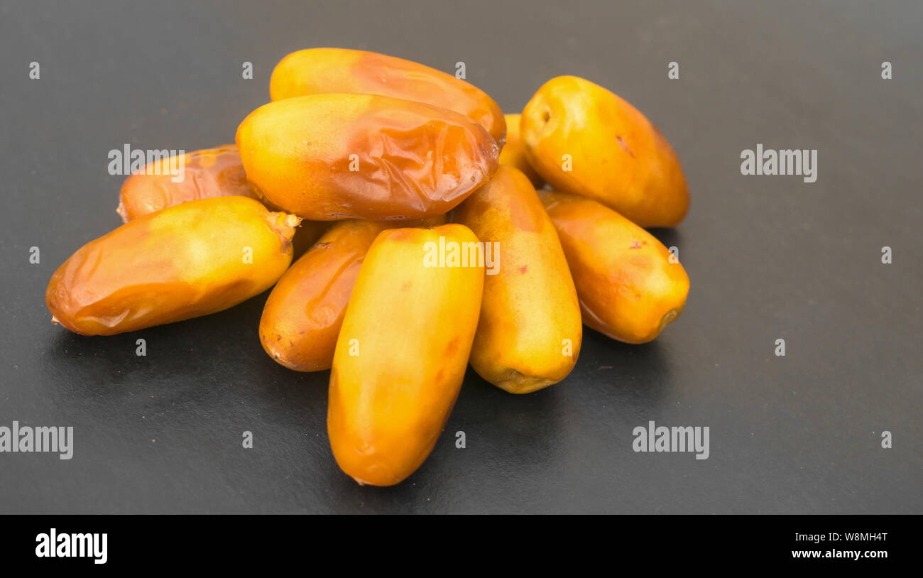 close up of fresh riped delicious yellow dates on black background ...