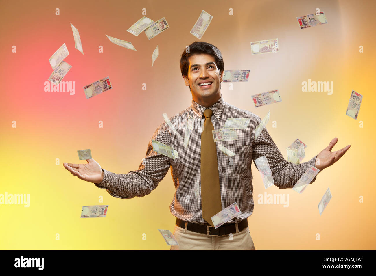 Money falling on a businessman standing with his arms outstretched ...