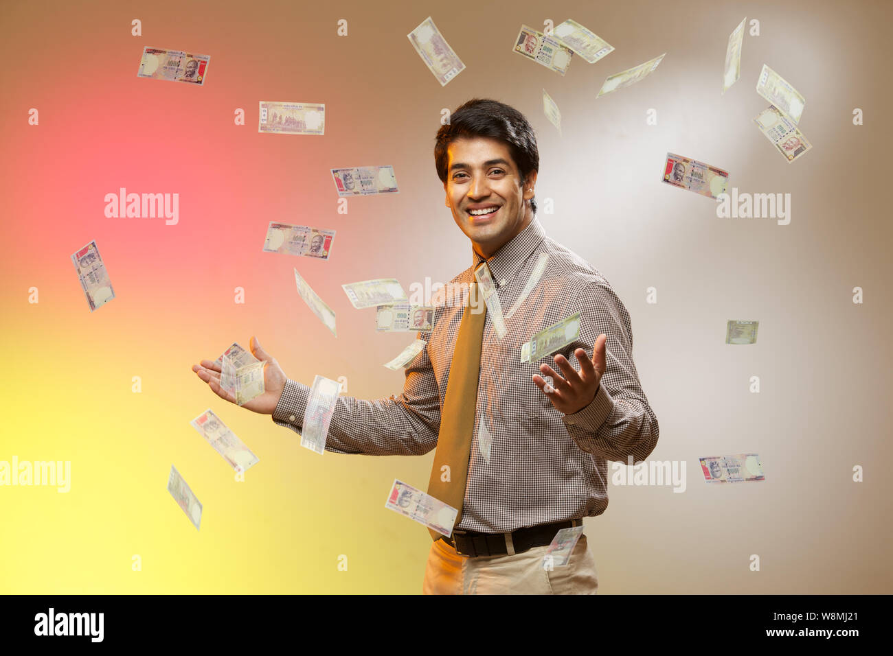 Money falling on a businessman standing with his arms outstretched ...