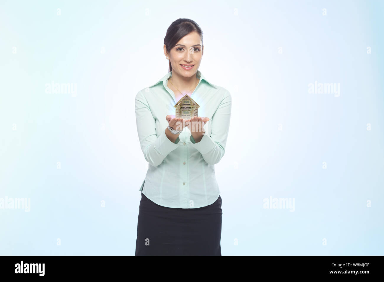 Real estate agent holding a model home made of Indian paper currency ...