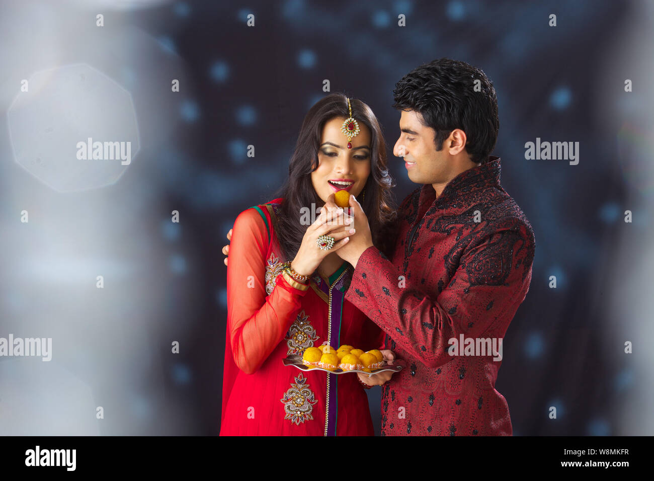 Young man feeding ladoo to his wife Stock Photo - Alamy