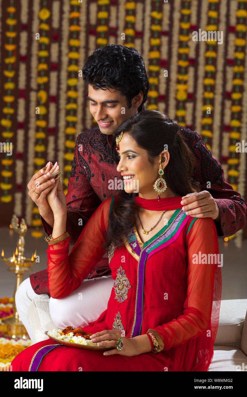 Young man putting on bangles in wife's hands Stock Photo - Alamy
