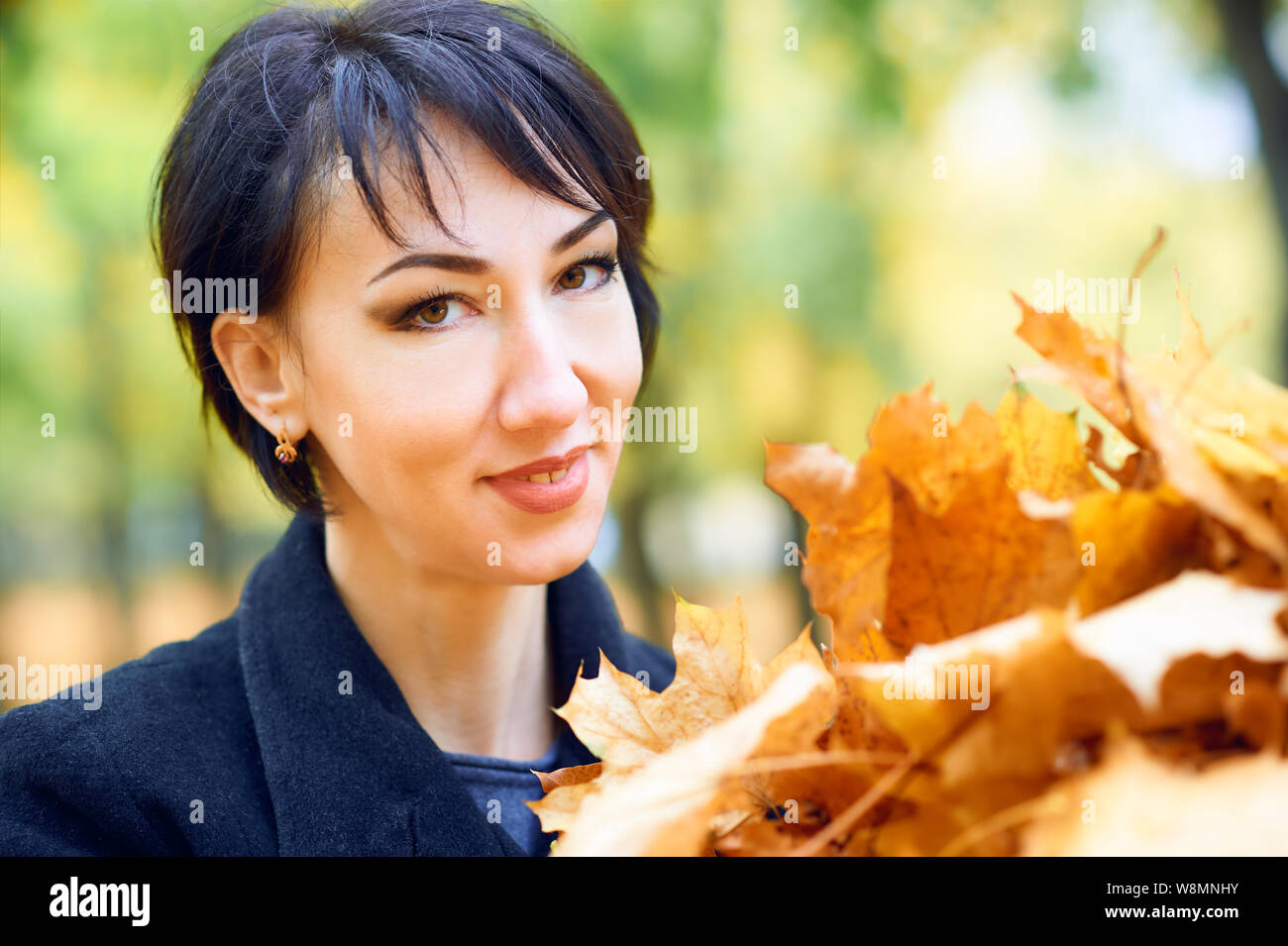 Beautiful woman posing with yellow leaves in autumn city park, fall ...