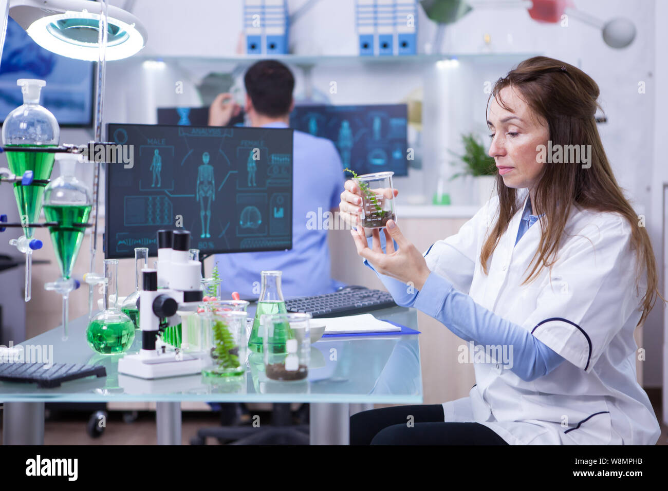 Female scientist with a microscope on her research lab. Test tubes ...