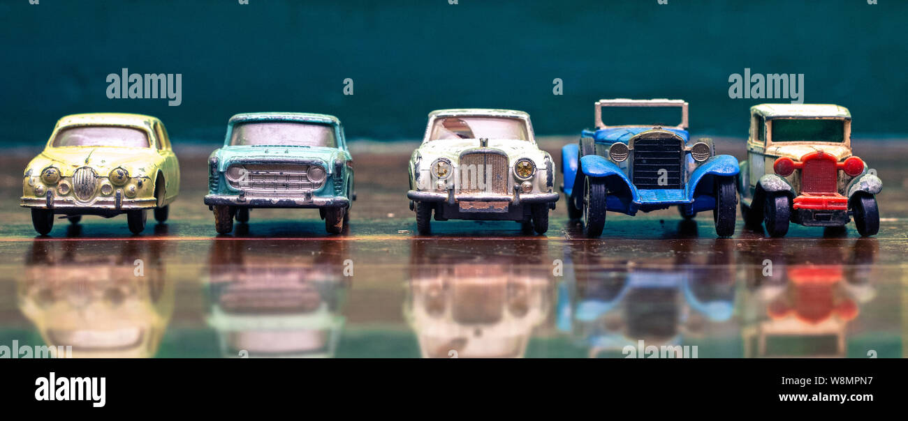 a line of retro toy cars parked on a old wooden floor with reflection ...