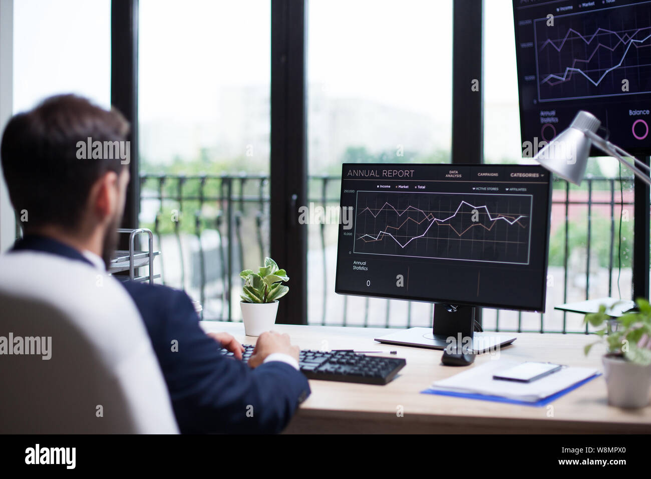 Back view of handsome young bearded business man typing on his computer ...