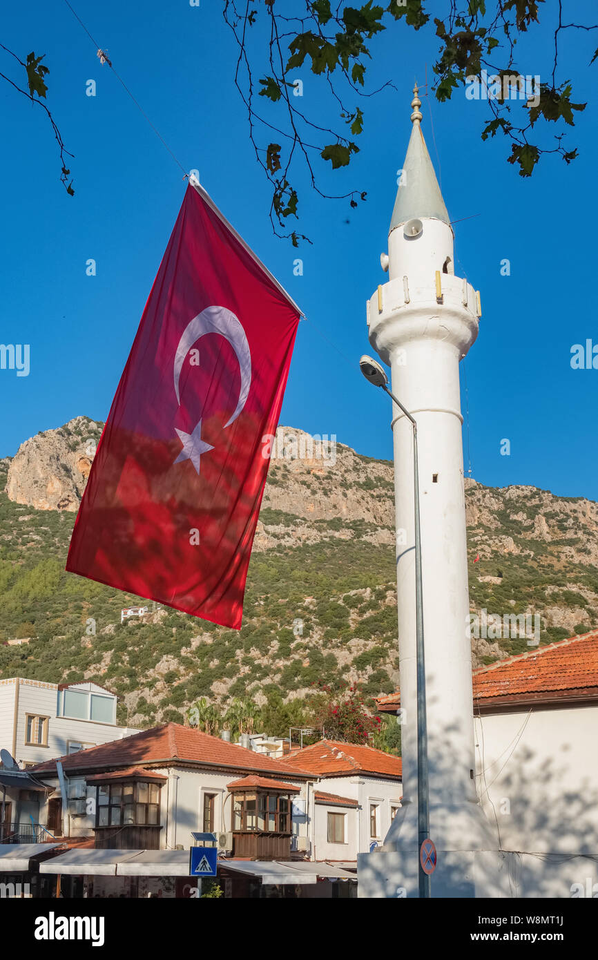 Turkish national flag and white minaret in mediterranean town Kas ...