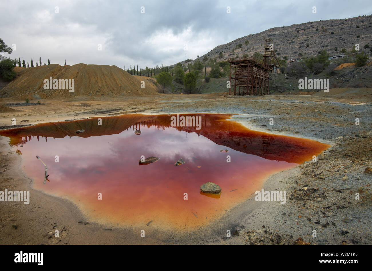 Abandoned copper mine with red toxic water and dramatic stormy cloudy ...