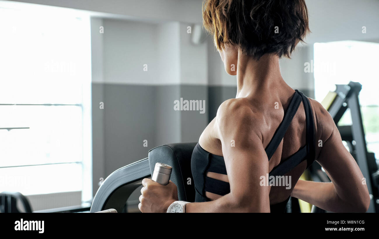 Sportive woman is doing exercises for spine muscles on block simulator ...