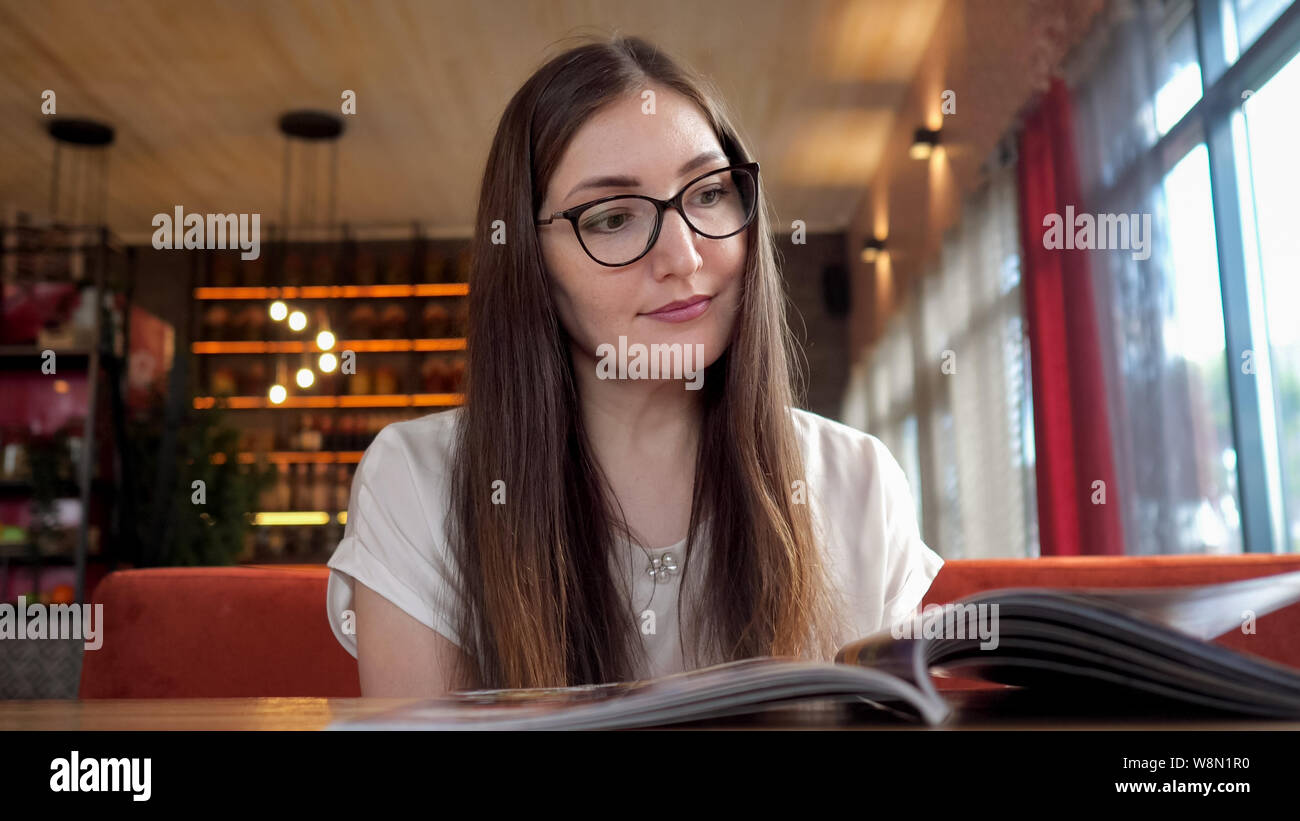 Beauty young woman in glasses reading menu. Smiling beautiful girl ...