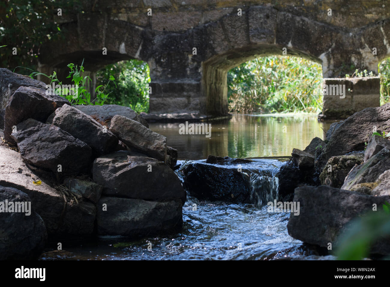 Beautiful ancient stone arch bridge over a river stream with reflection ...