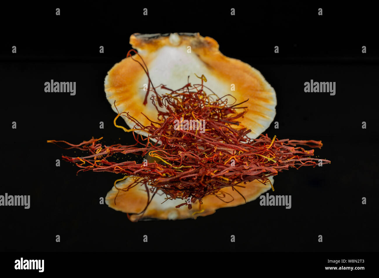 Lot of whole dry shaffron thread in seashell isolated on black glass ...