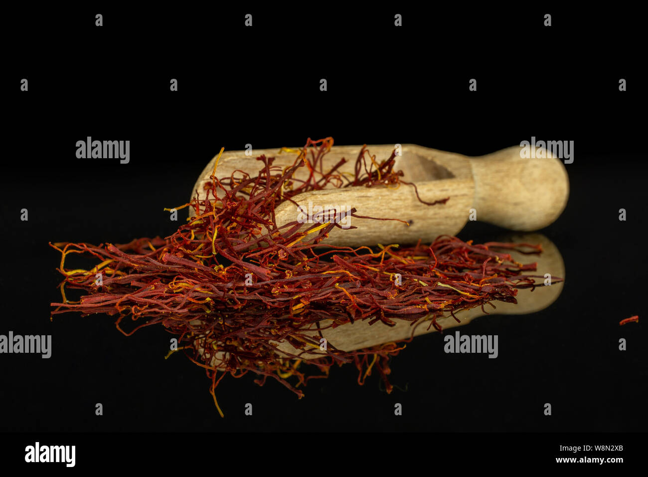 Lot of whole dry shaffron thread with wooden scoop isolated on black ...