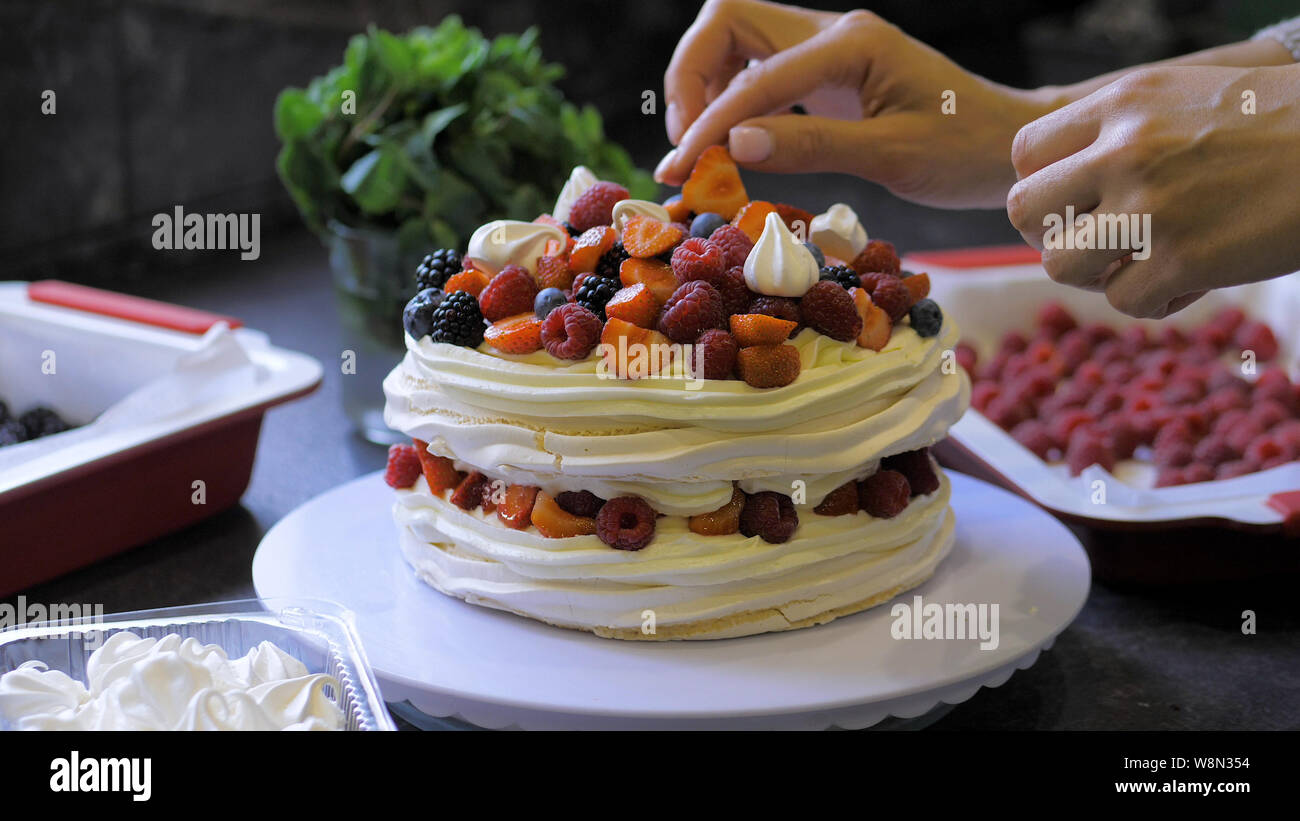 The process of making dessert Anna Pavlova with berries and cream Stock ...