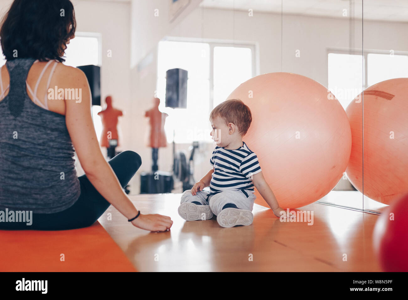Portrait of happy young fit mother doing exercise at gym and having fun ...