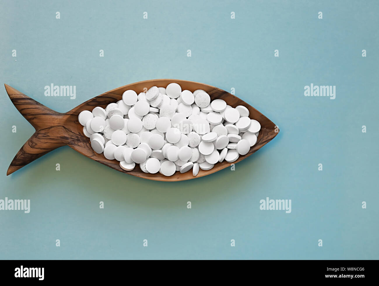 Calcium pills in a wooden dish in the form of a fish. Fish is rich in ...