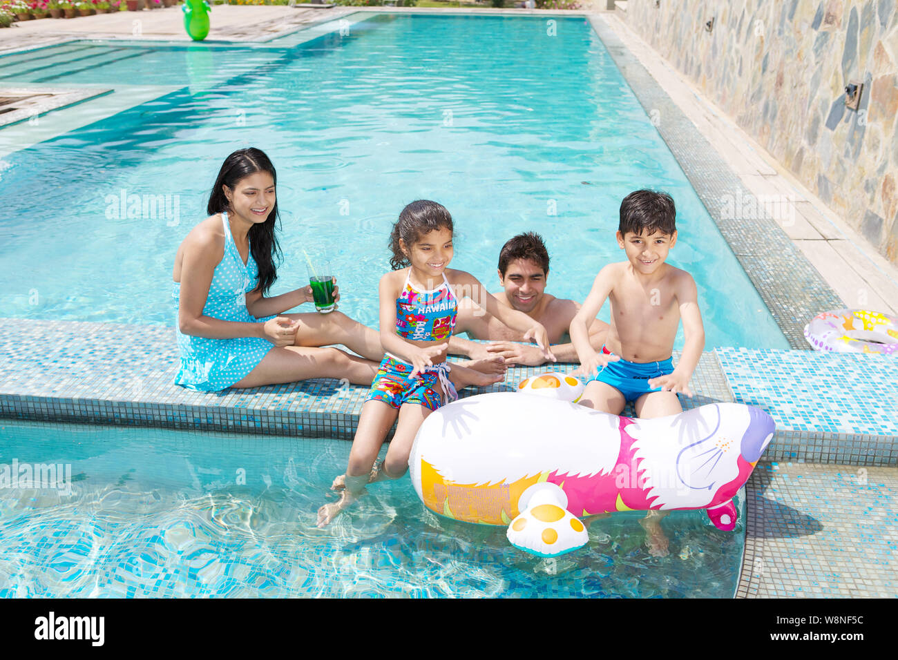 Family playing in a swimming pool Stock Photo - Alamy