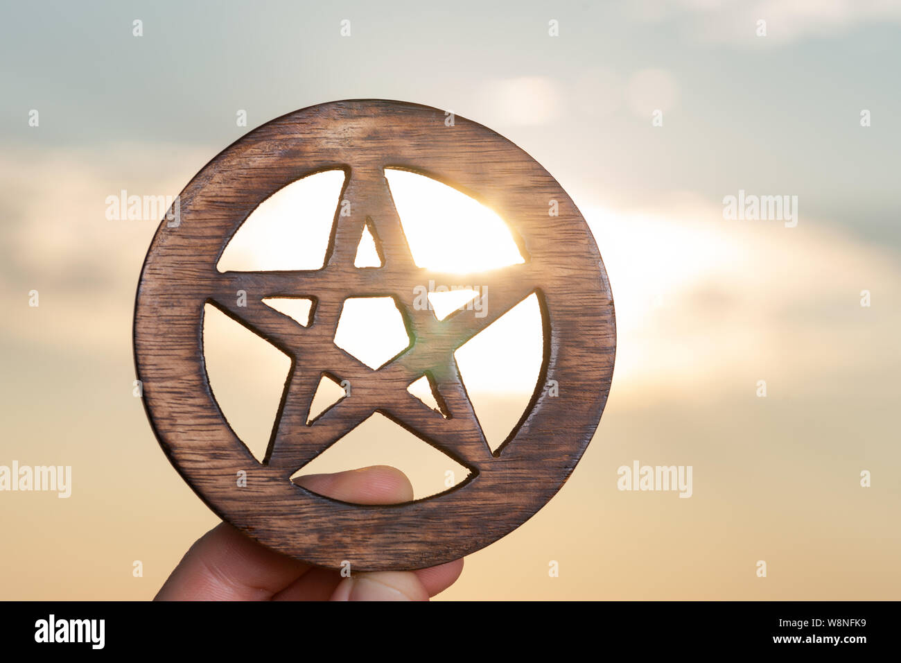 Woman's hand holding Wooden encircled Pentagram symbol at sunrise in ...