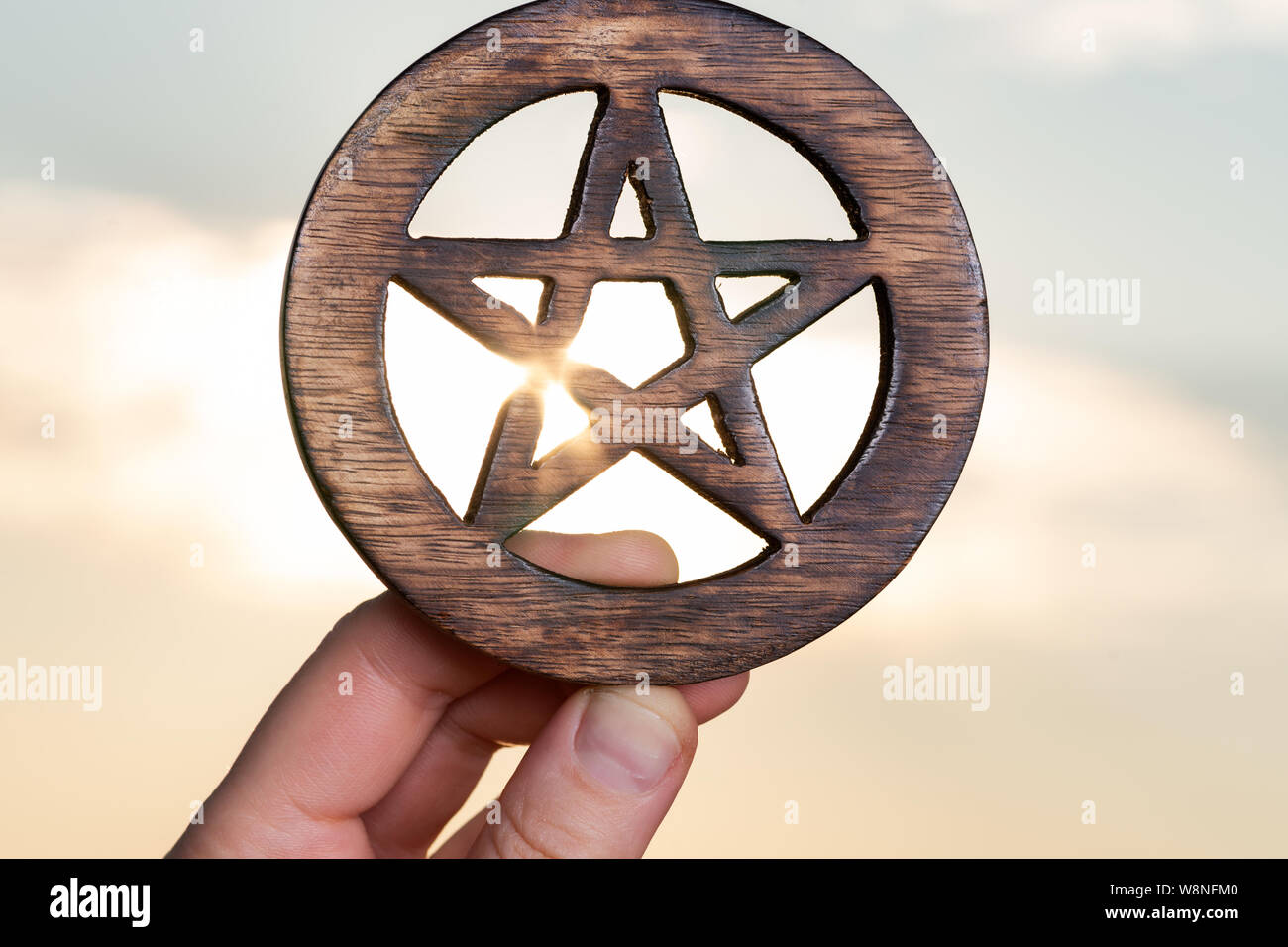 Woman's hand holding Wooden encircled Pentagram symbol at sunrise in ...
