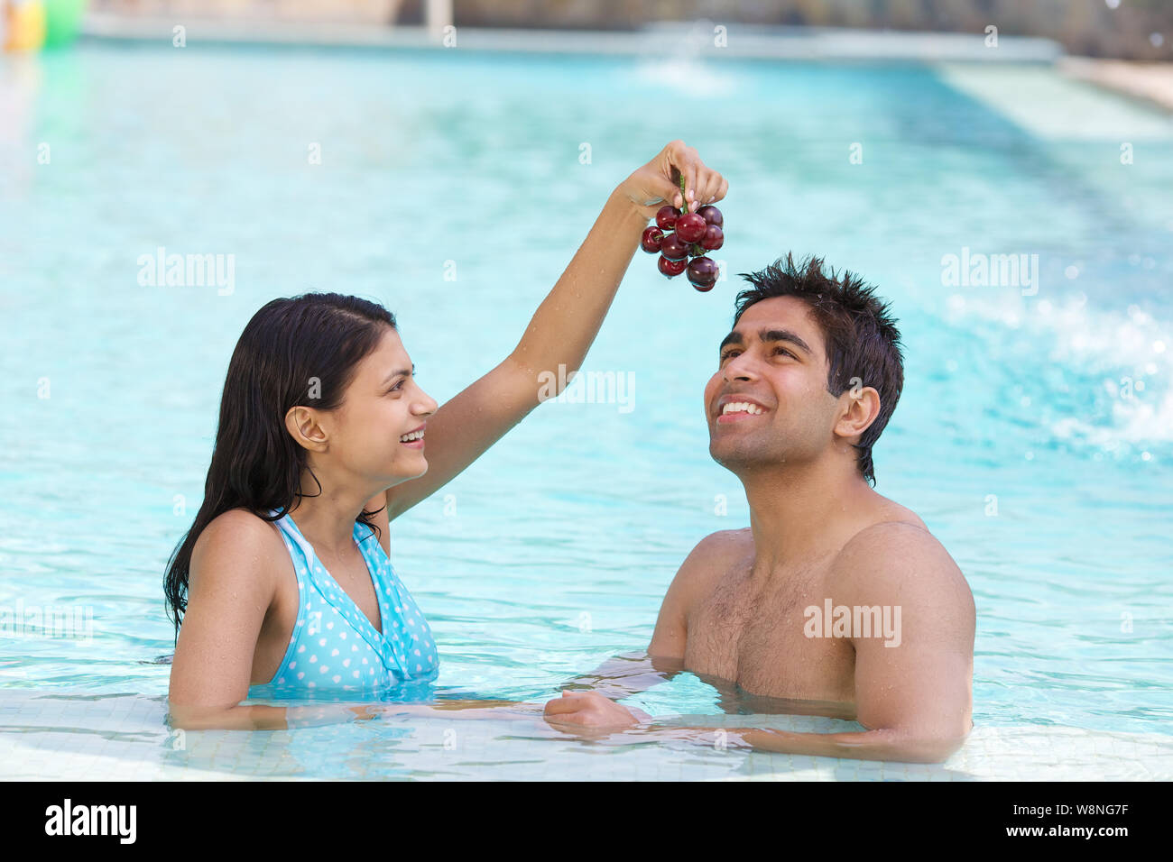 Girlfriend feeding grapes to her boyfriend in a swimming pool Stock Photo - Alamy