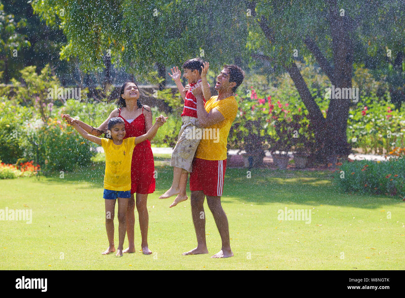 Family enjoying rain in a garden Stock Photo - Alamy