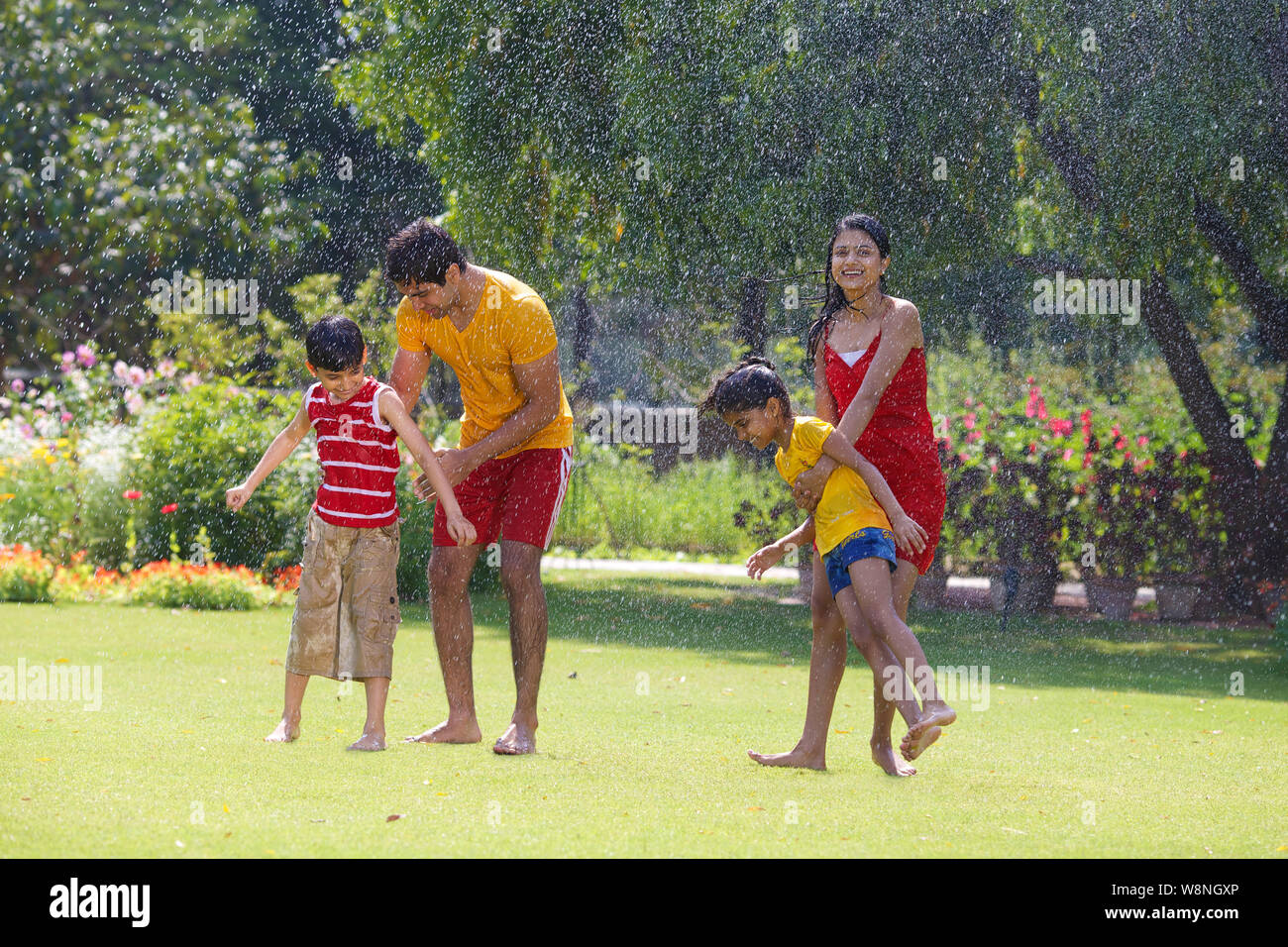 Family enjoying rain in a garden Stock Photo - Alamy