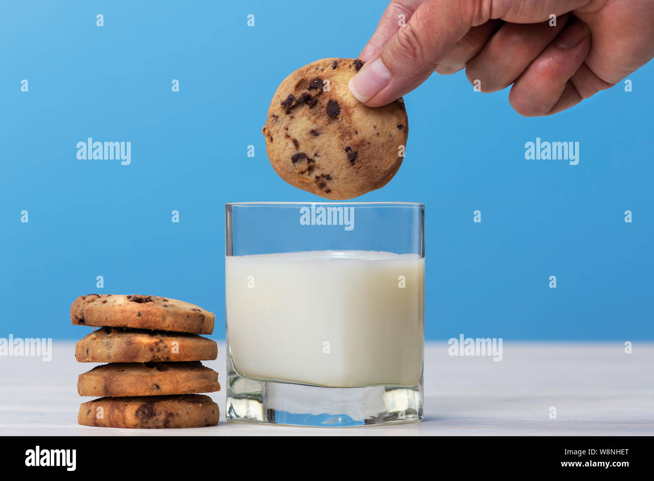 dunking chocolate chip cookies into a glass of milk Stock Photo - Alamy