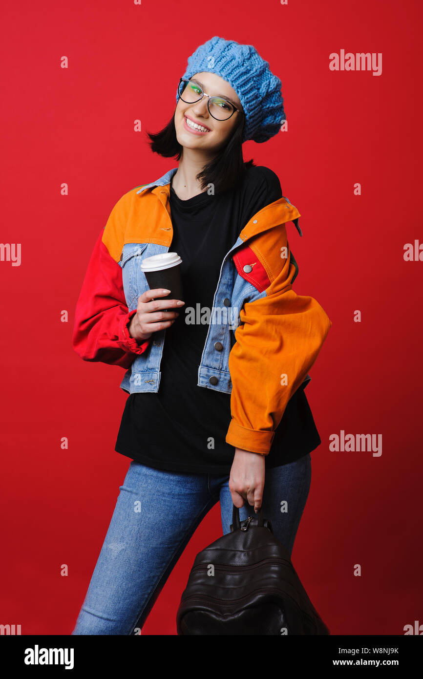 Cheerful brunette woman in colorful warm clothes standing with takeaway ...