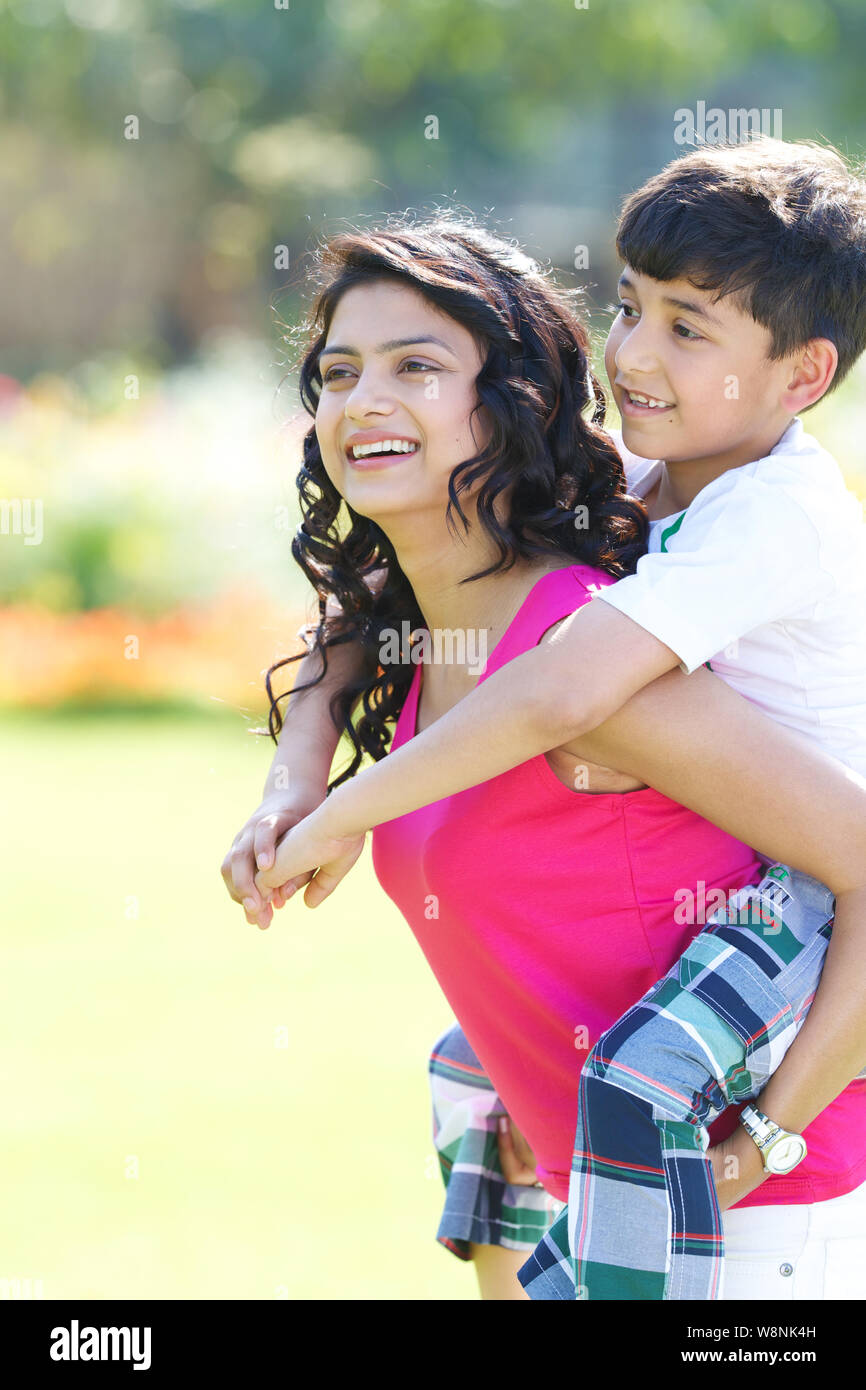 Mother giving a piggyback ride to her son in a garden Stock Photo - Alamy