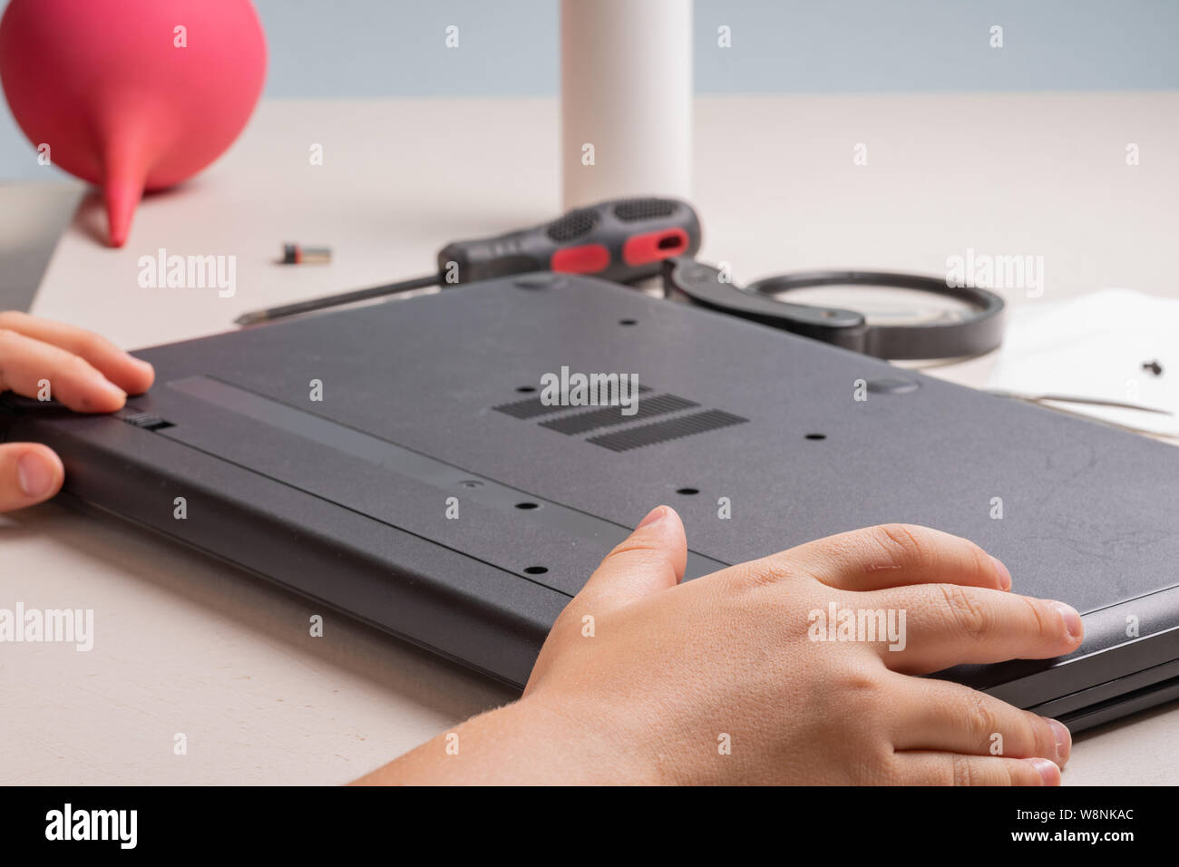 A boy of 10 years old is sorting a laptop for cleaning and maintenance ...
