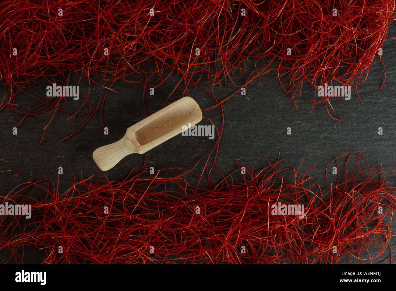 Lot of whole red chili pepper threads with wooden scoop flatlay on grey ...