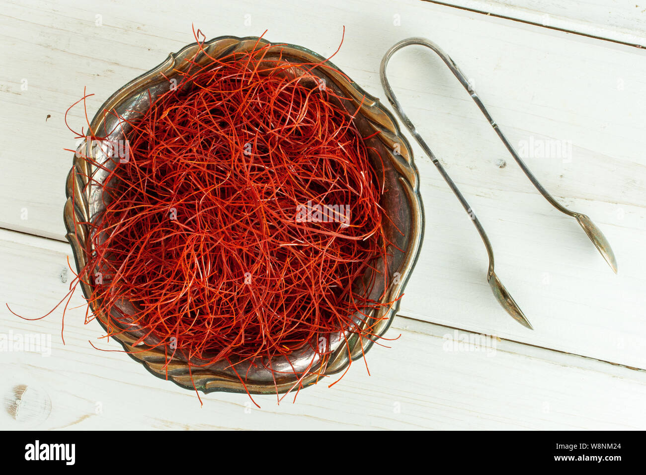 Lot of whole red chili pepper threads in old iron bowl with sugar tongs ...