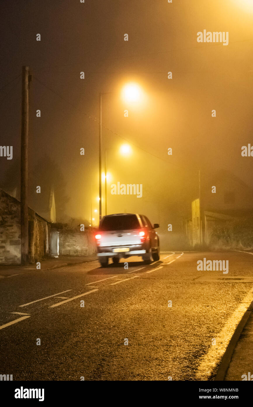 Pickup truck driving along a road at night in Consett, County Durham ...
