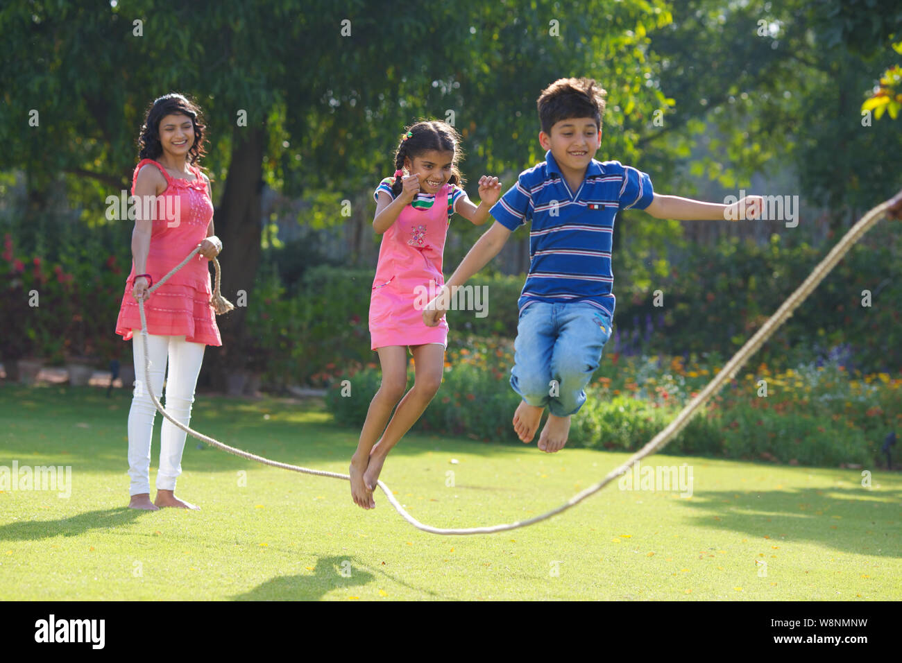 Family playing with a rope in a garden Stock Photo - Alamy