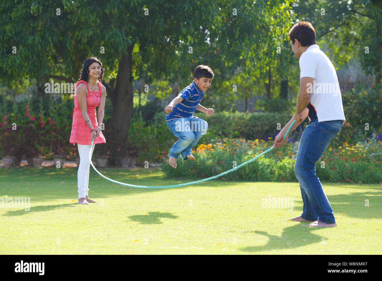 Family playing with a rope in a garden Stock Photo - Alamy