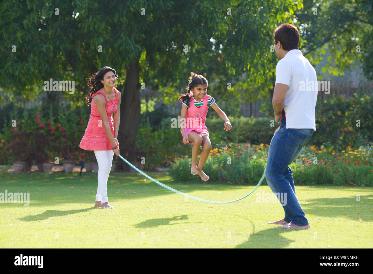 Family playing with a rope in a garden Stock Photo - Alamy
