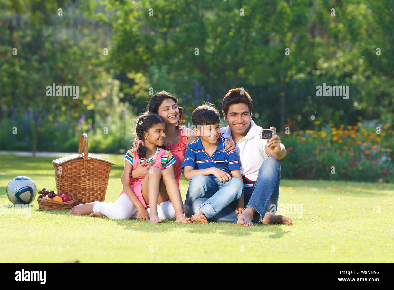 Family taking a picture of themselves with a digital camera in a garden ...
