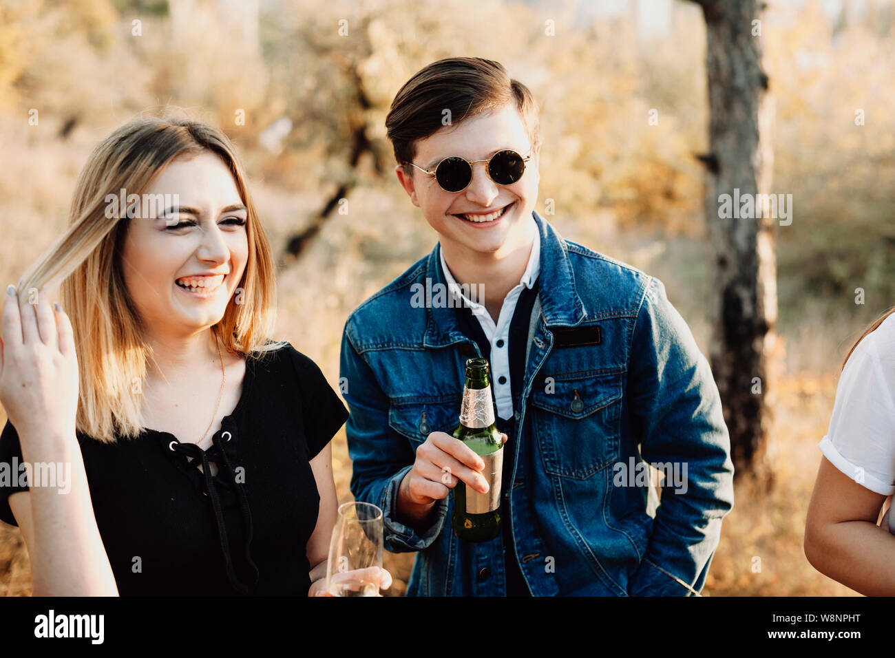 Handsome young guy with bottle of beer and lovely female with glass of ...