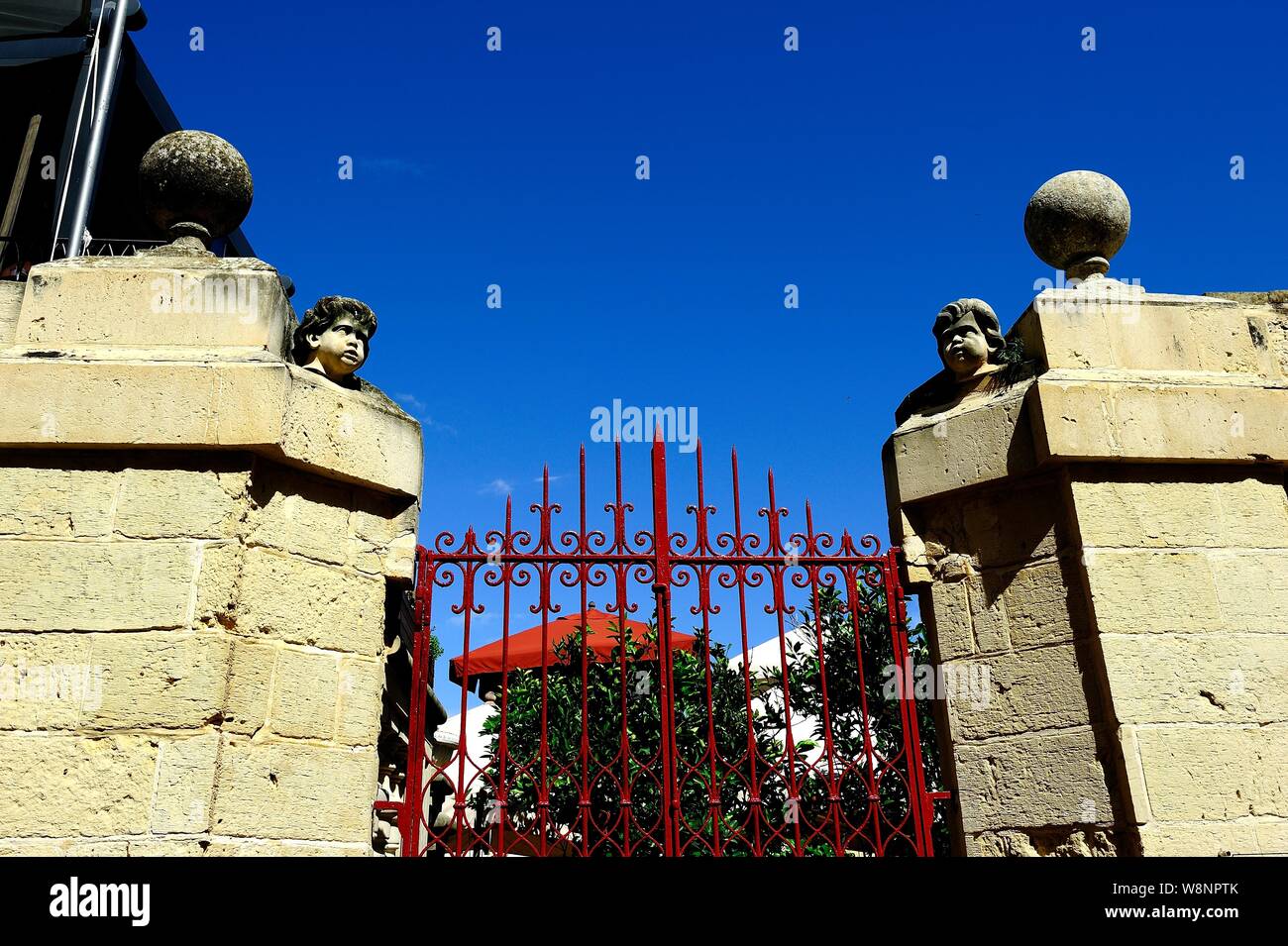 statues guarding the red metal gateway Stock Photo - Alamy