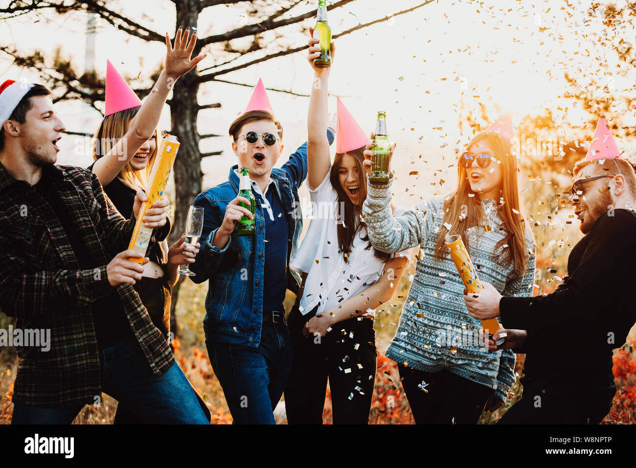 Young people with beer screaming and exploding party crackers while ...